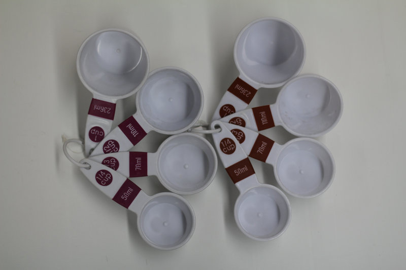 Measuring cup bianca messa, prodotti della cucina con la maniglia di tocco morbido